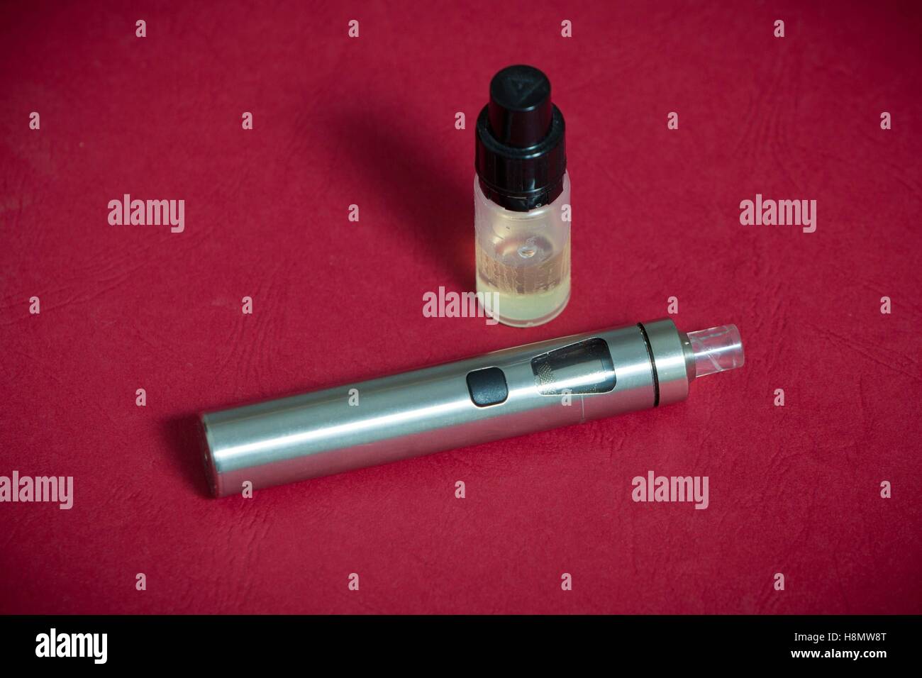 product photo of a silver e-cigarette with liquid on red background ...