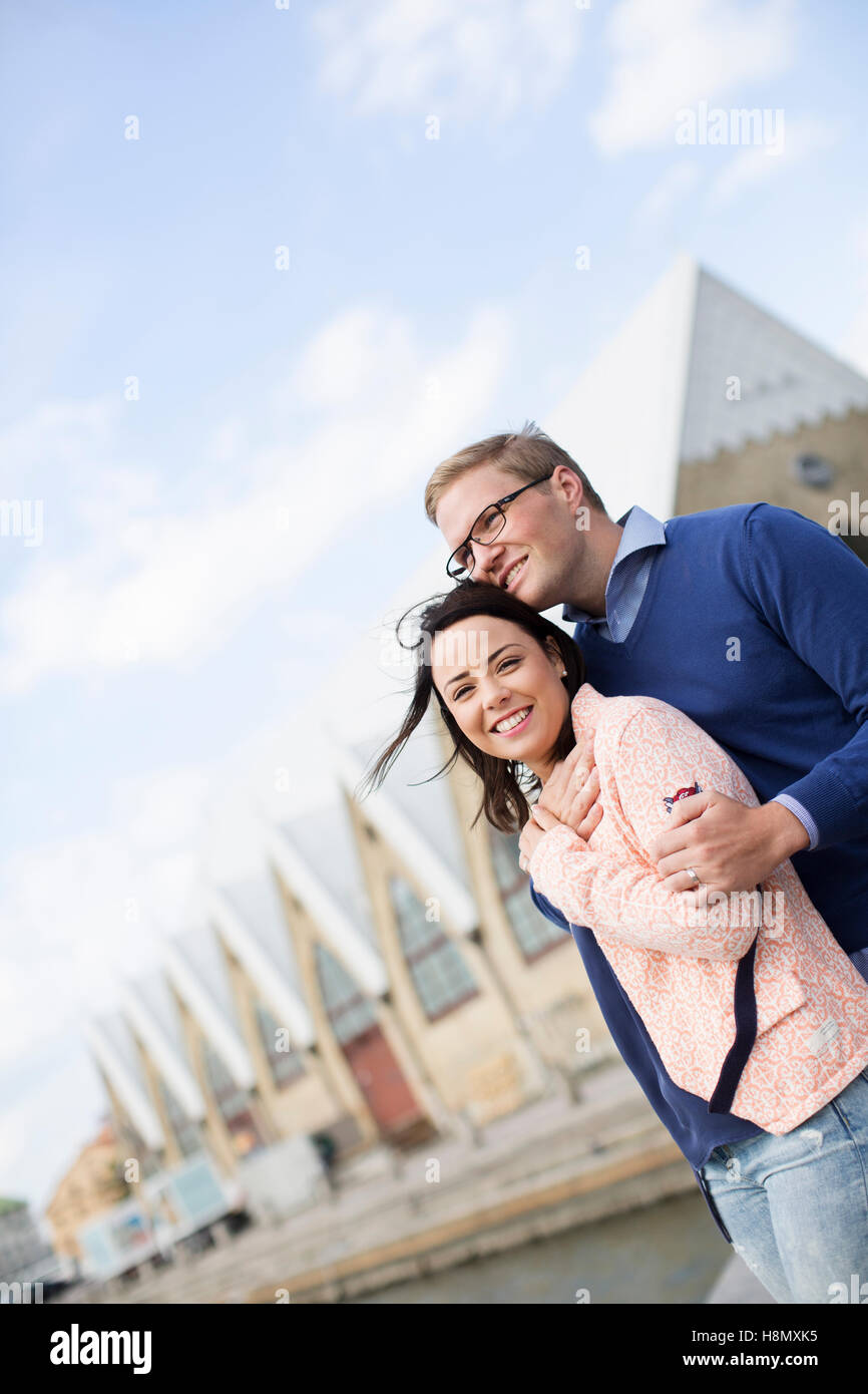 Smiling young couple against buildings Stock Photo - Alamy