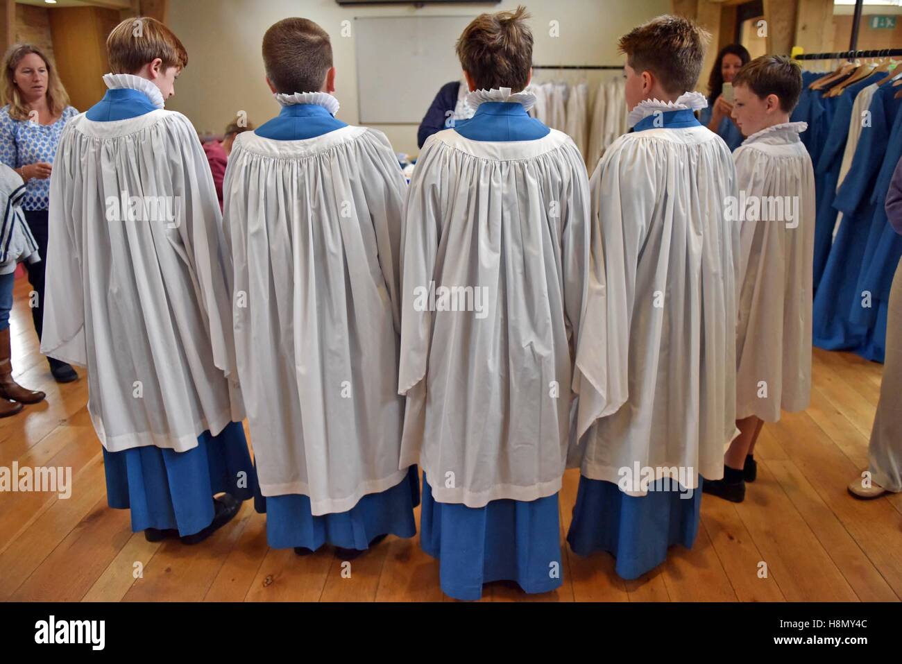 Five surpliced boy choristers at cassock fitting before first evensong ...