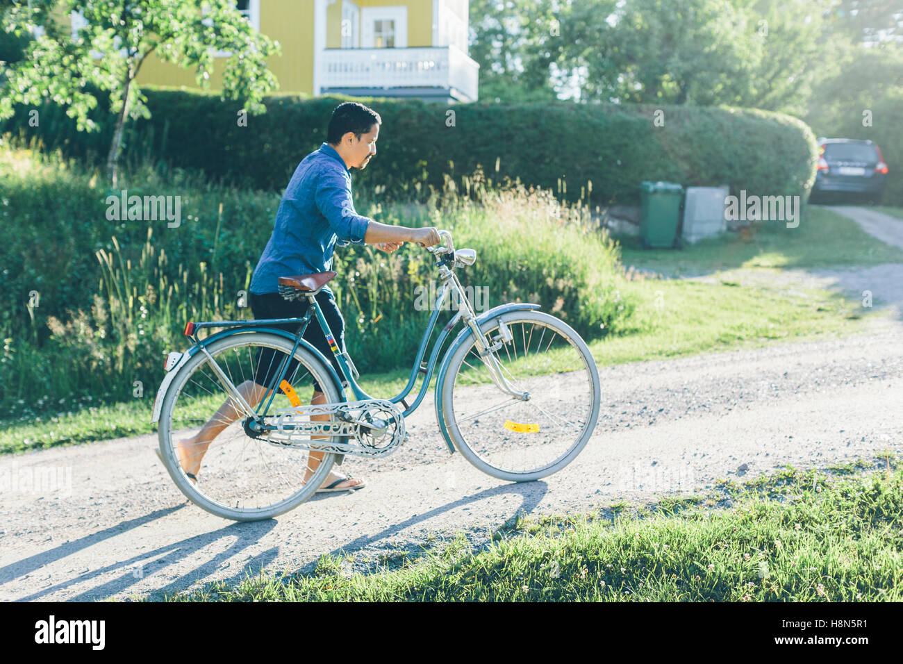 Man pushing bicycle on road Stock Photo - Alamy