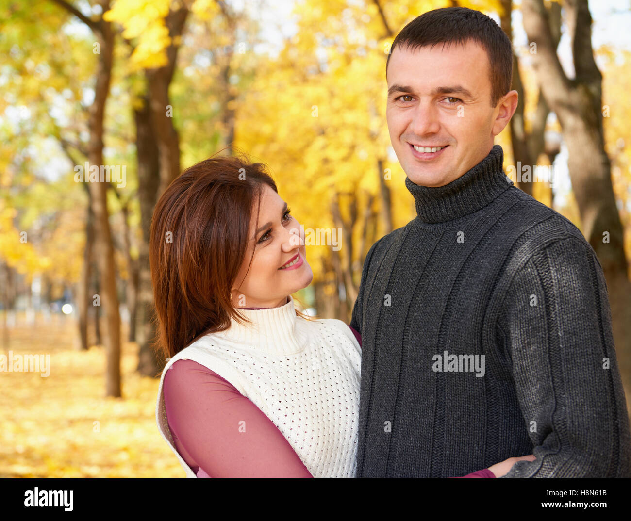 happy adult couple embrace in autumn city park, trees with yellow ...
