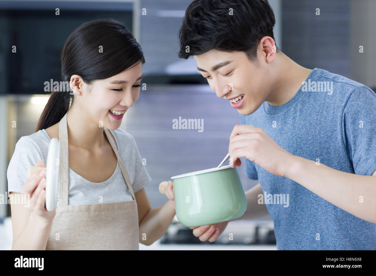 Happy young Chinese couple cooking in kitchen Stock Photo - Alamy