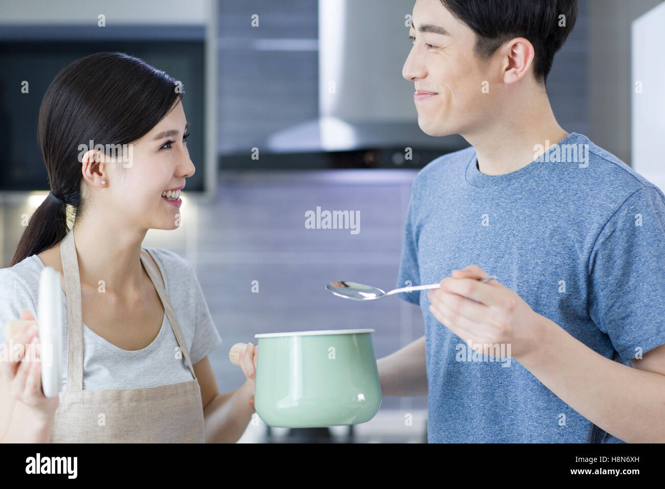 Happy young Chinese couple cooking in kitchen Stock Photo - Alamy