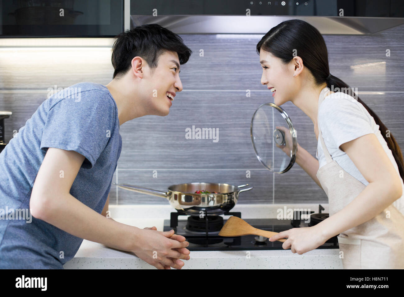 Happy young Chinese couple cooking in kitchen Stock Photo - Alamy
