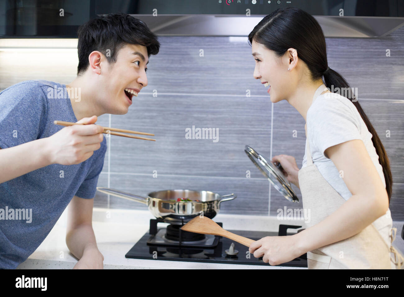 Happy young Chinese couple cooking in kitchen Stock Photo - Alamy
