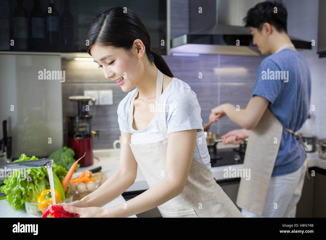 Happy young Chinese couple cooking in kitchen Stock Photo - Alamy