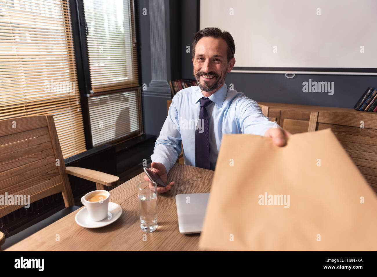 Good looking pleasant man giving you an envelope Stock Photo - Alamy
