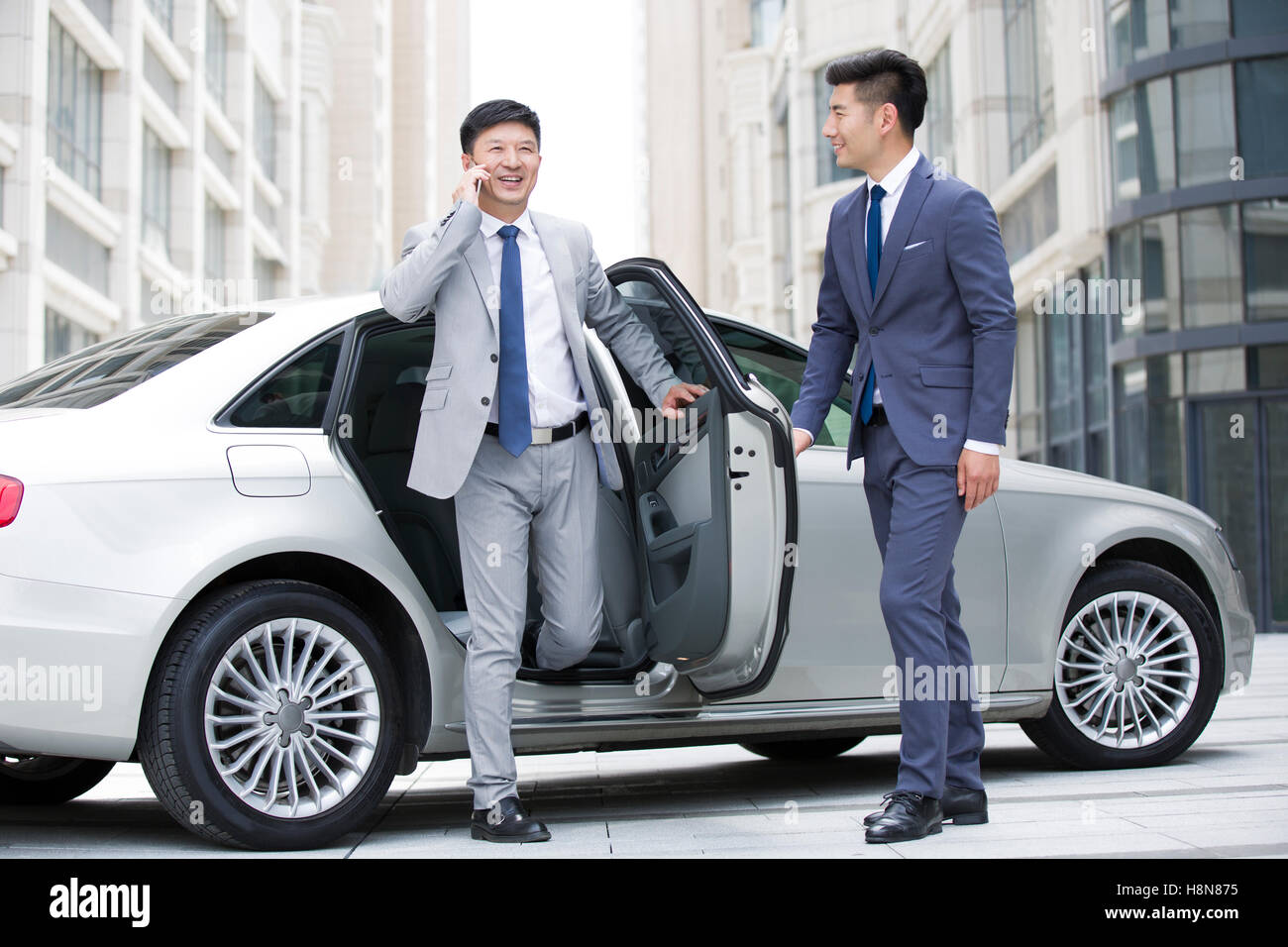 Confident Chinese businessman getting off car Stock Photo - Alamy