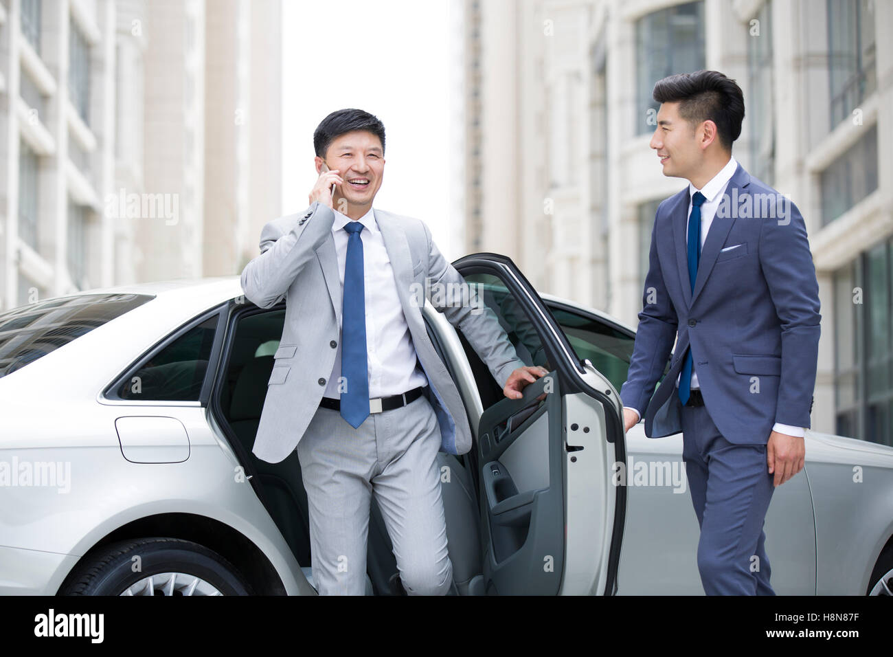 Confident Chinese businessman getting off car Stock Photo - Alamy