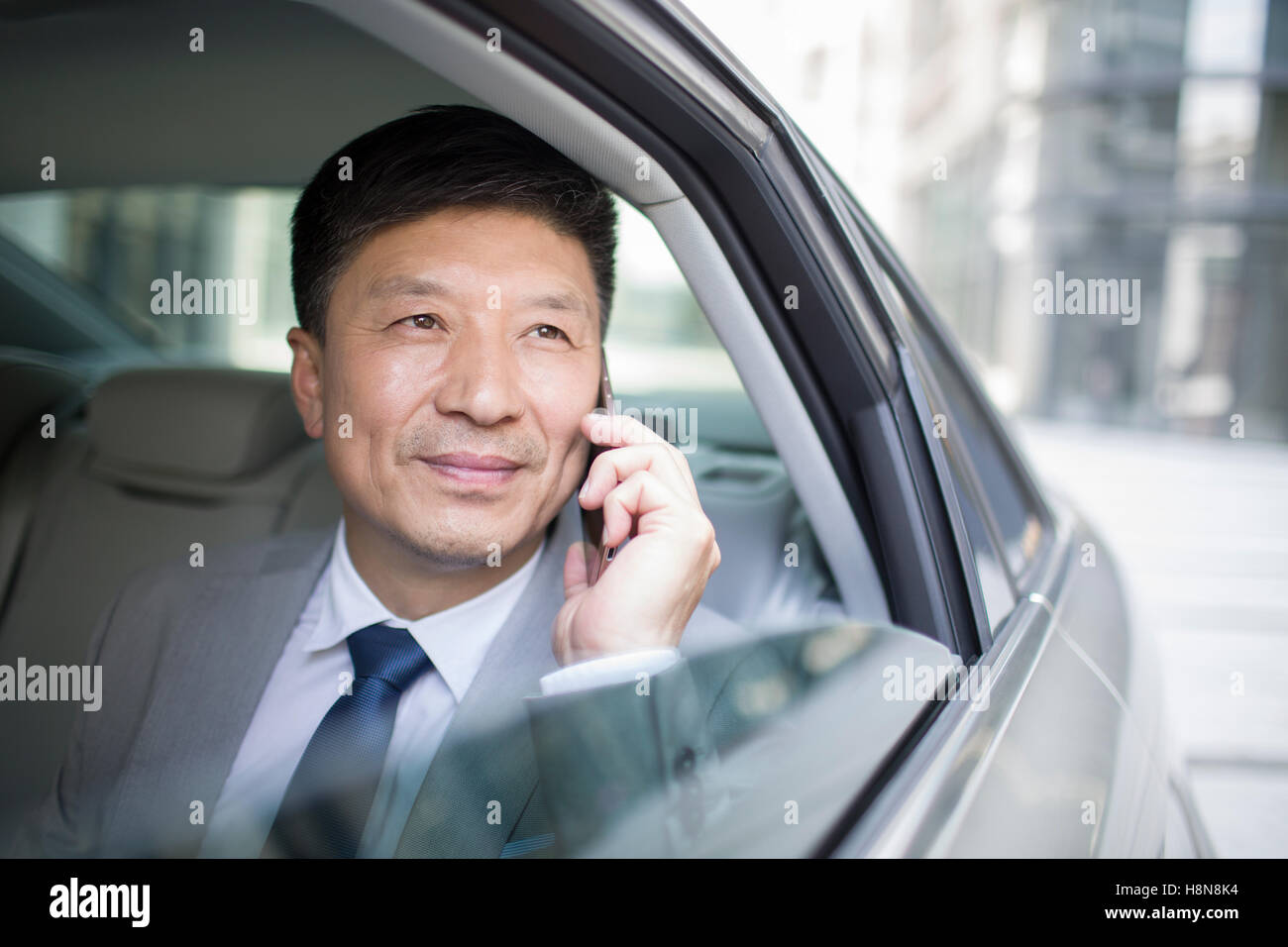 Confident Chinese businessman talking on cell phone inside car Stock ...