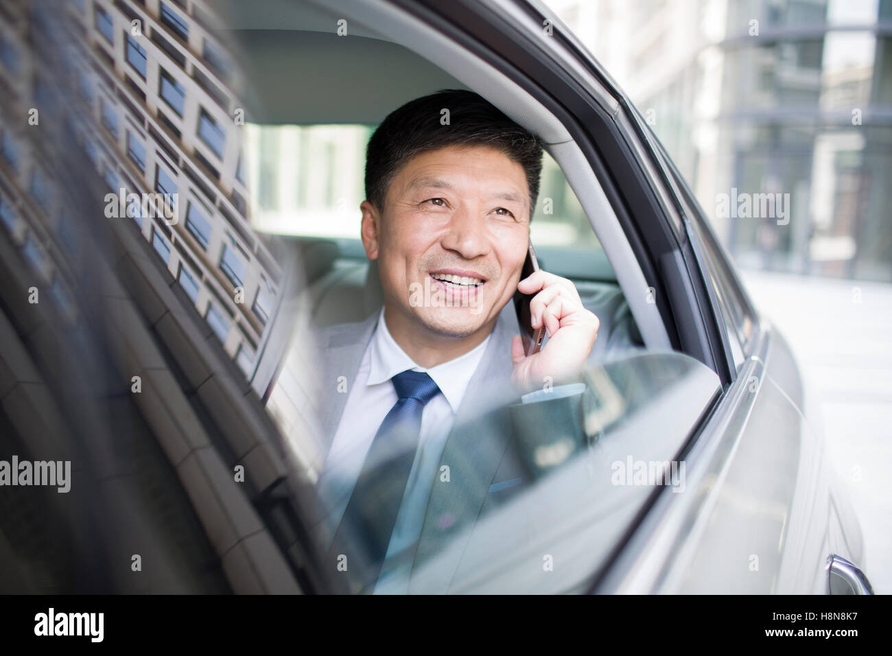 Confident Chinese businessman talking on cell phone inside car Stock Photo - Alamy