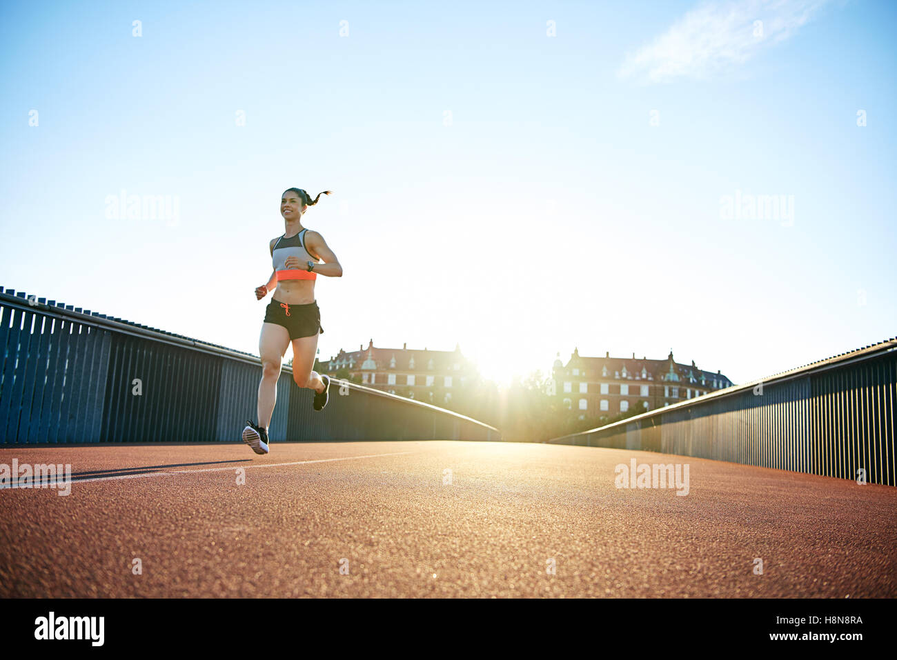 Low angle view of woman running down concrete and iron railing bridge ...