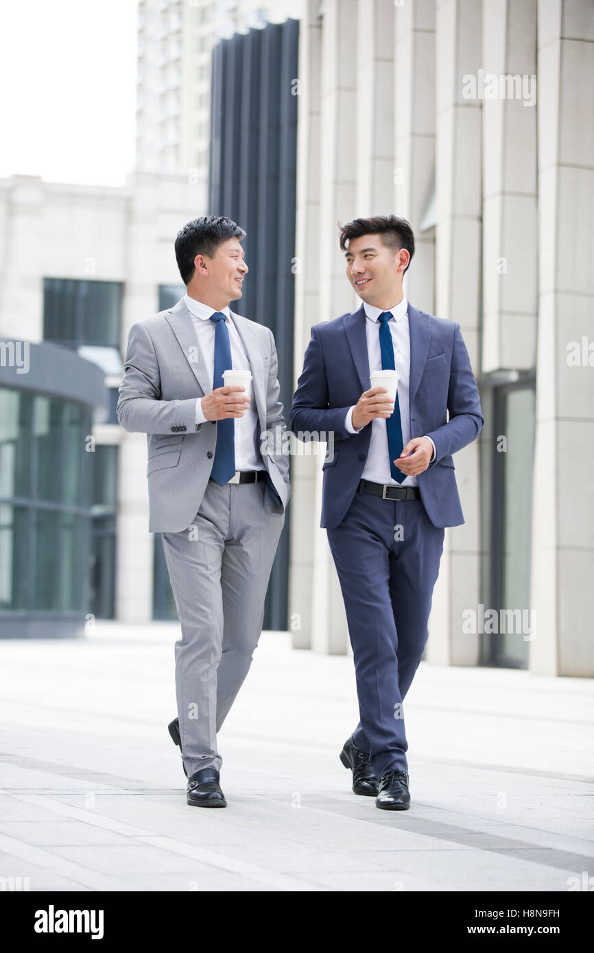 Confident Chinese businessmen talking and walking outdoors Stock Photo ...