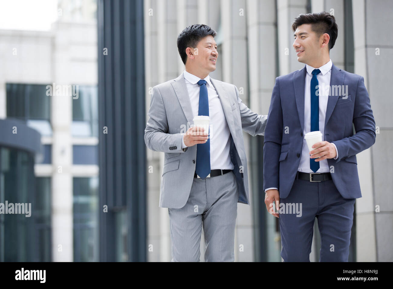 Confident Chinese businessmen talking and walking outdoors Stock Photo ...