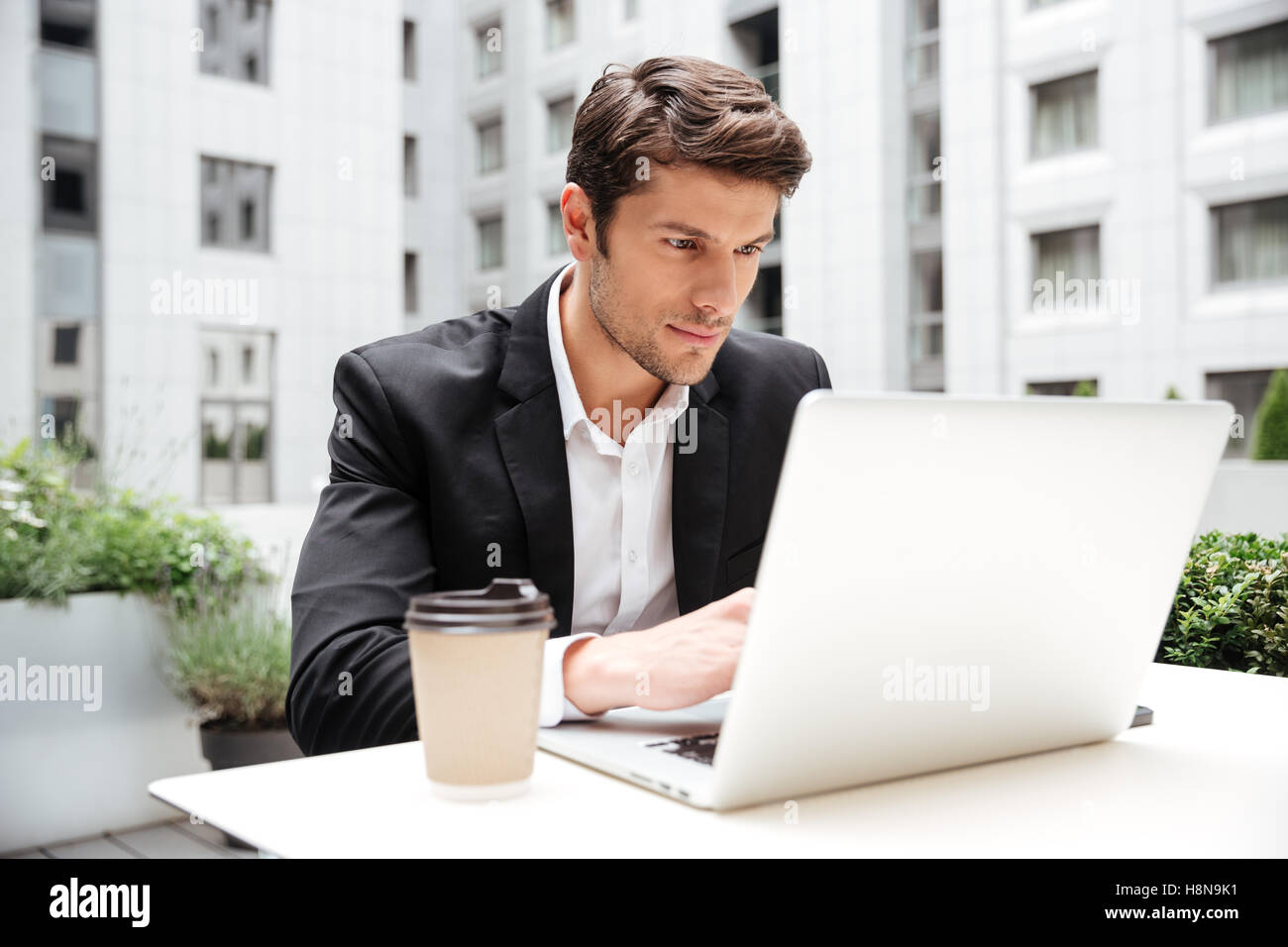 Concentrated young businessman using laptop in outdoor cafe Stock Photo ...