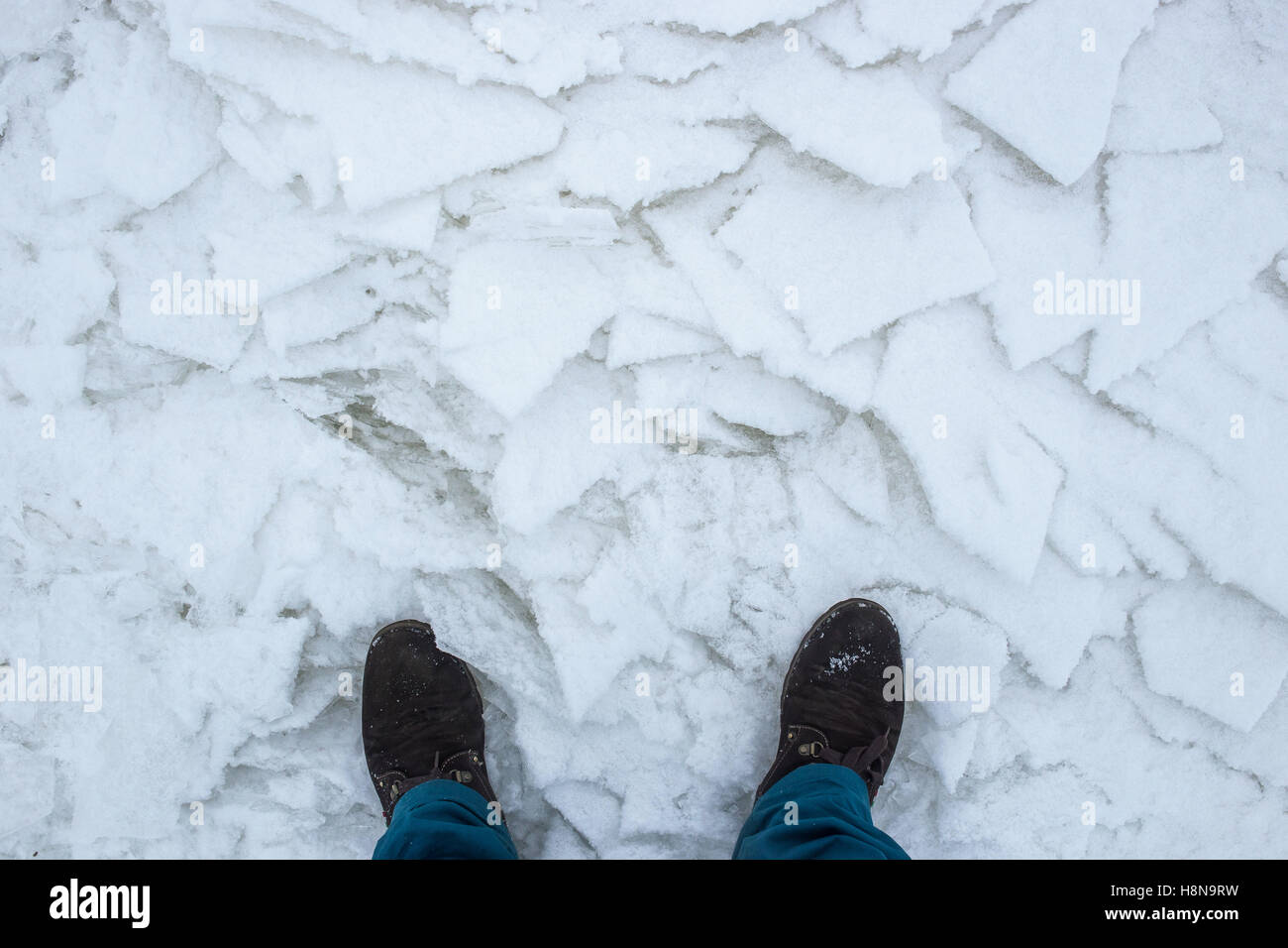 Hiking boots on river shattered ice, top view. Concept of danger an ...