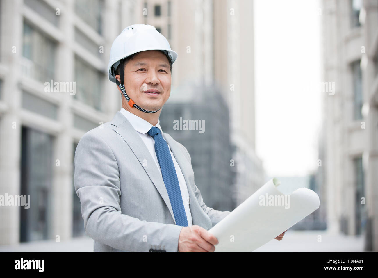 Chinese male architect looking at view with blueprint outdoors Stock ...