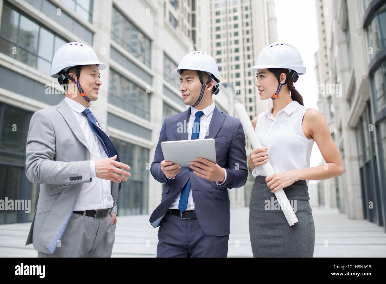 Confident Chinese architects talking with digital tablet outdoors Stock ...