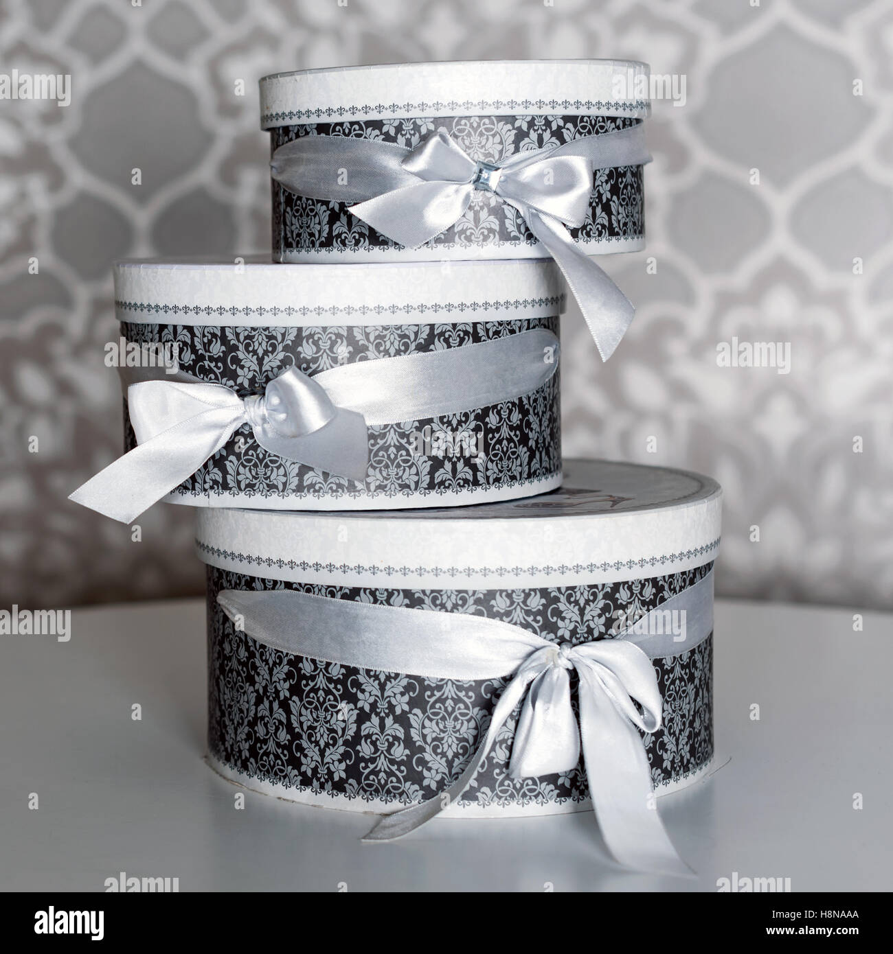 Three round celebration gift boxes with silver ribbon bows on white ...