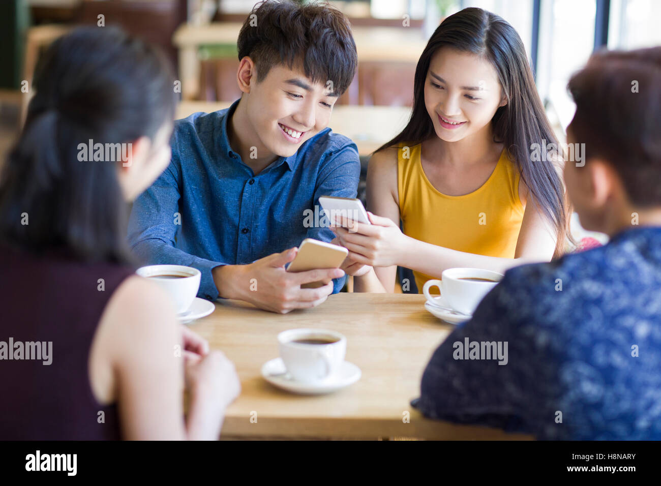 Young Chinese friends using smart phones in cafe Stock Photo - Alamy