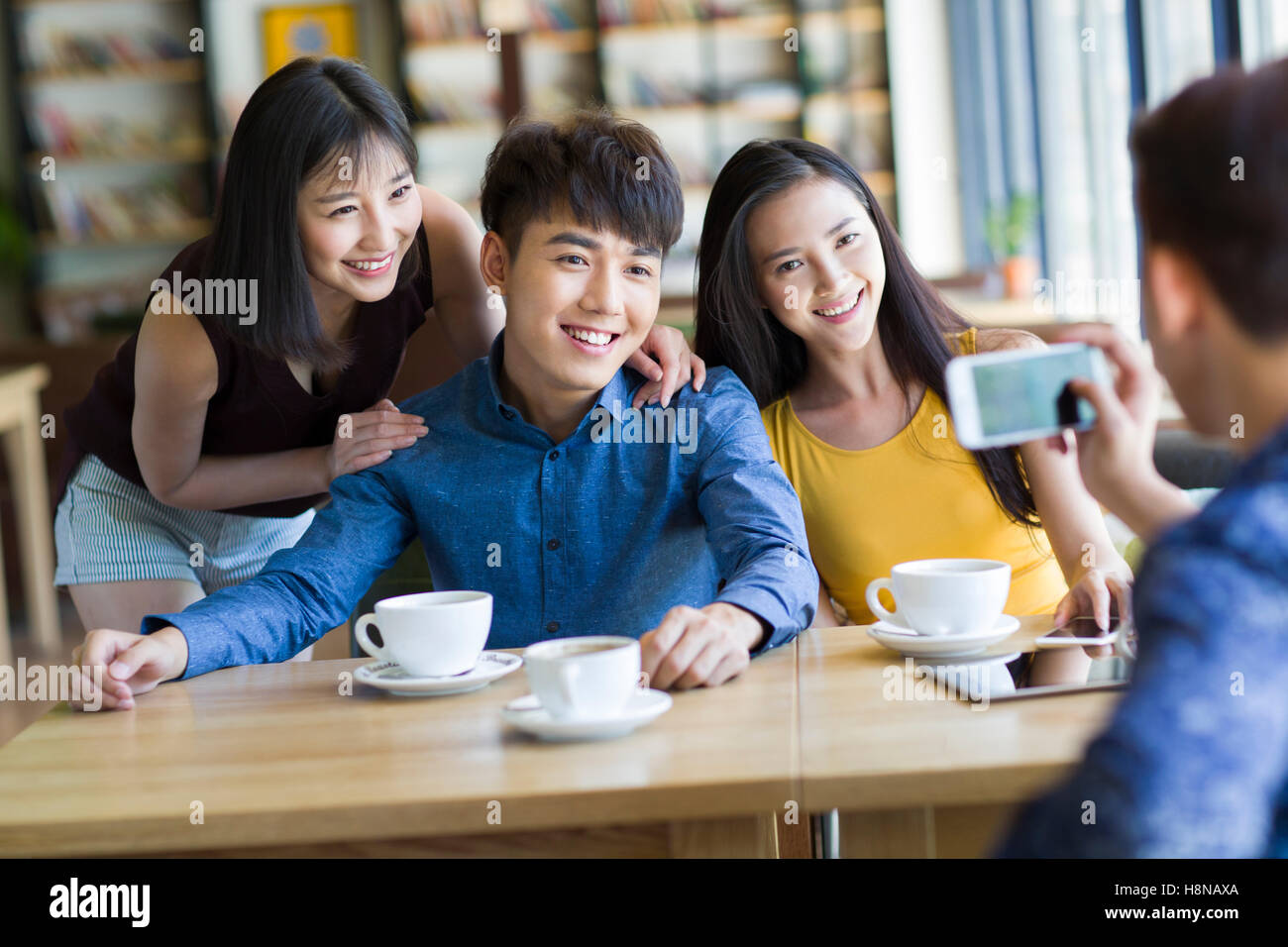 Young Chinese friends taking photos in cafe Stock Photo - Alamy