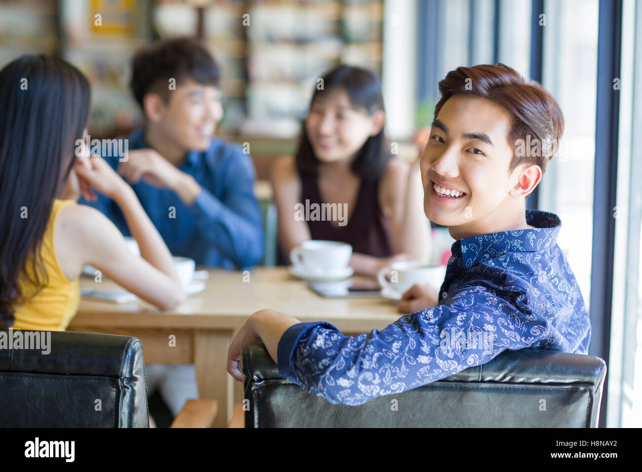Young Chinese man drinking coffee with friends in cafe Stock Photo - Alamy