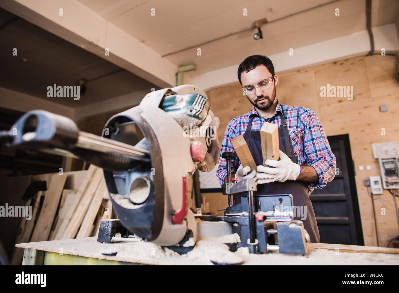Framing contractor using a circular cut off saw to trim wood studs ...