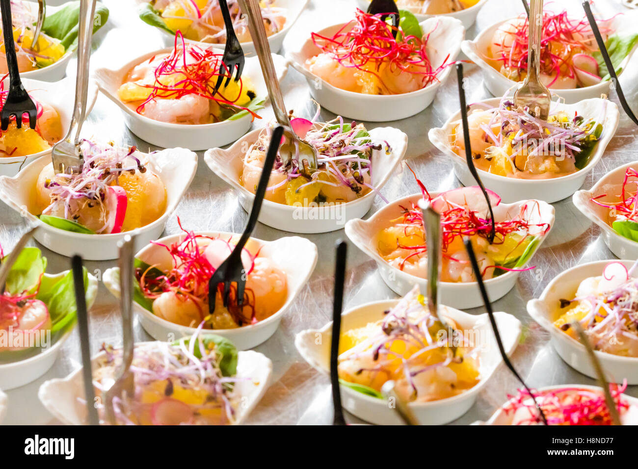 Colorful snacks (appetizers) in white cups with forks on table. Healthy ...
