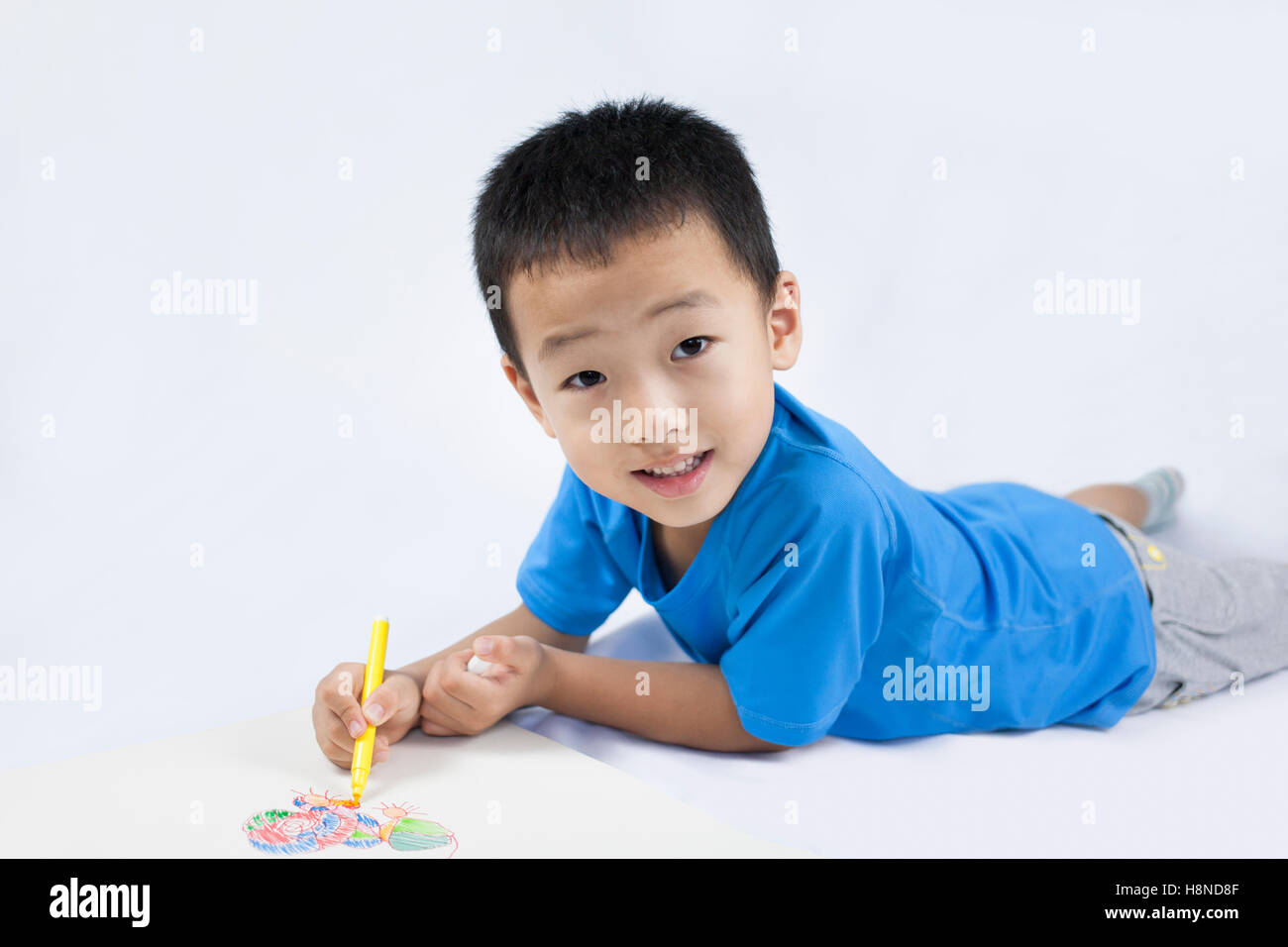 Happy little Chinese boy coloring while lying on the floor Stock Photo ...