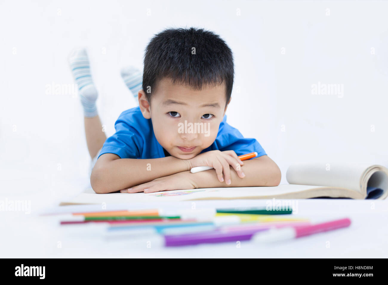 Happy little Chinese boy coloring while lying on the floor Stock Photo ...