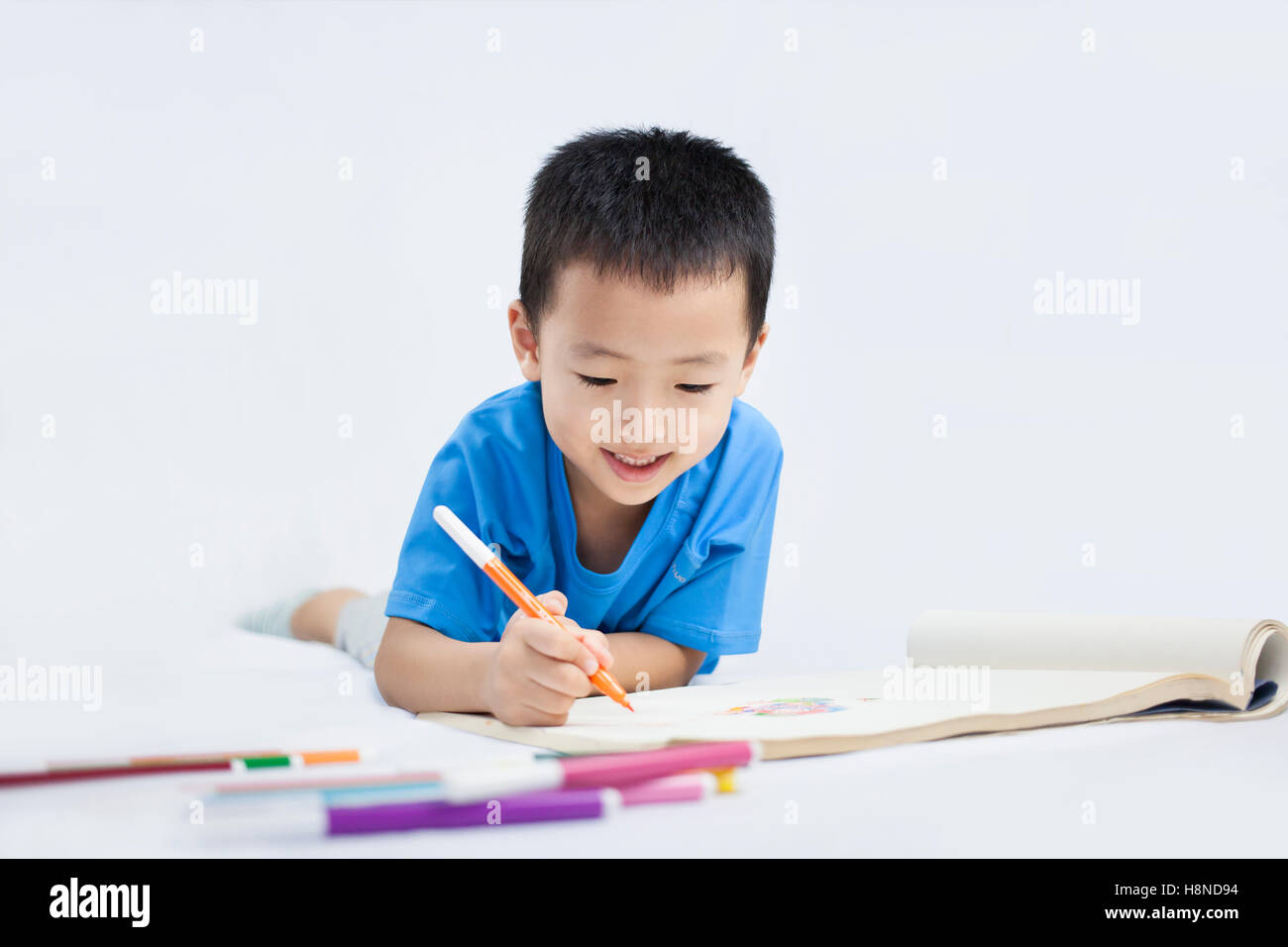 Happy little Chinese boy coloring while lying on the floor Stock Photo ...