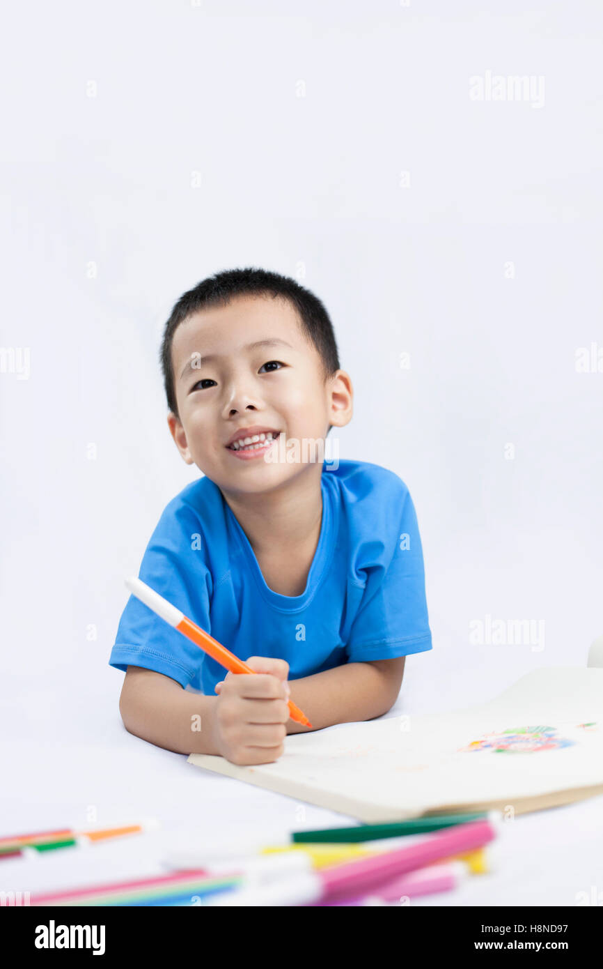 Happy little Chinese boy coloring while lying on the floor Stock Photo ...