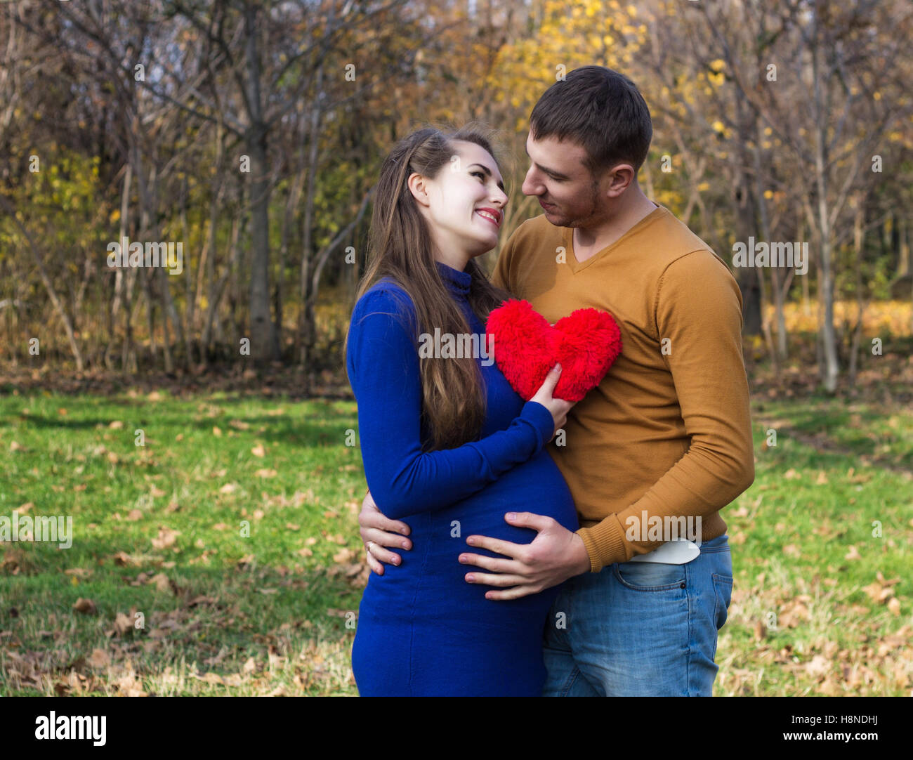 Happy pregnant couple hugging each other. She holds a soft toy in the ...
