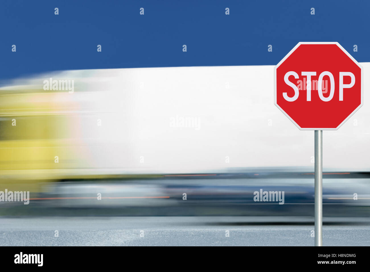 Red stop road sign, motion blurred truck vehicle traffic in background ...