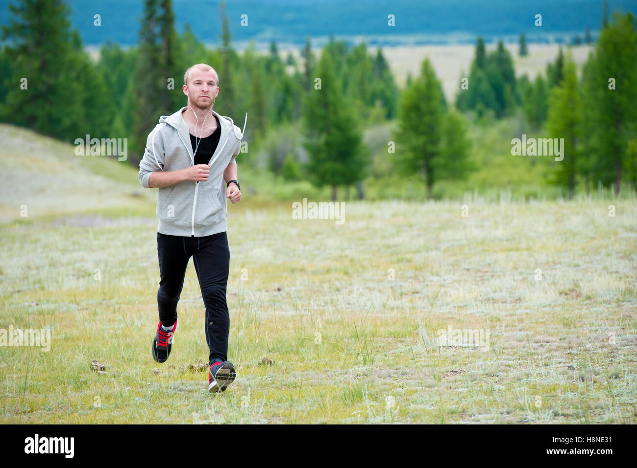 Man running on grass field at mountain background Stock Photo - Alamy