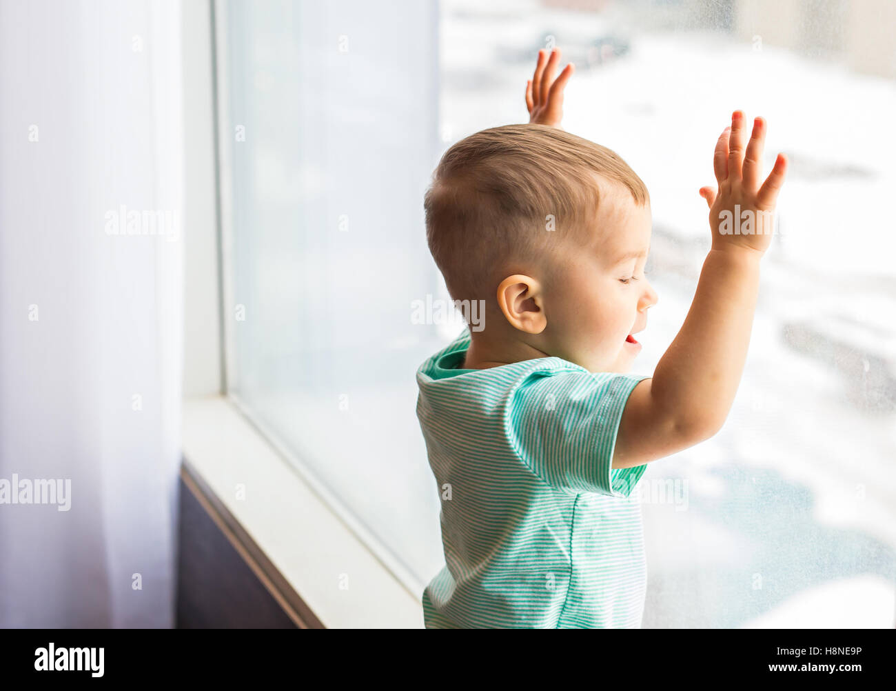 Little boy looking through window Stock Photo - Alamy