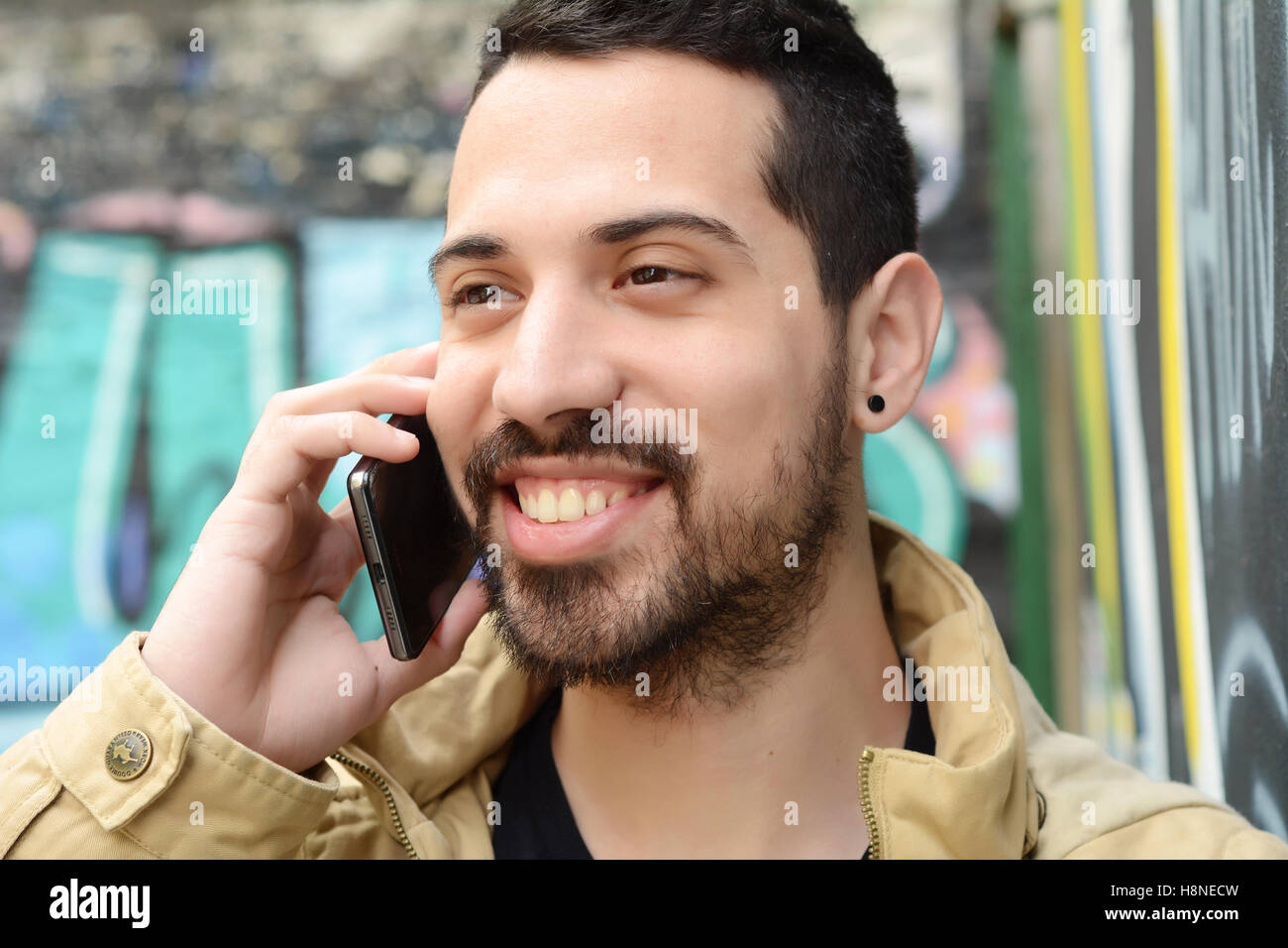 Handsome young latin man talking on the phone. Trendy and urban scene ...