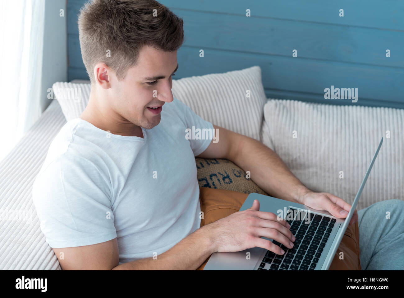 Cheerful young smiling man using laptop Stock Photo - Alamy
