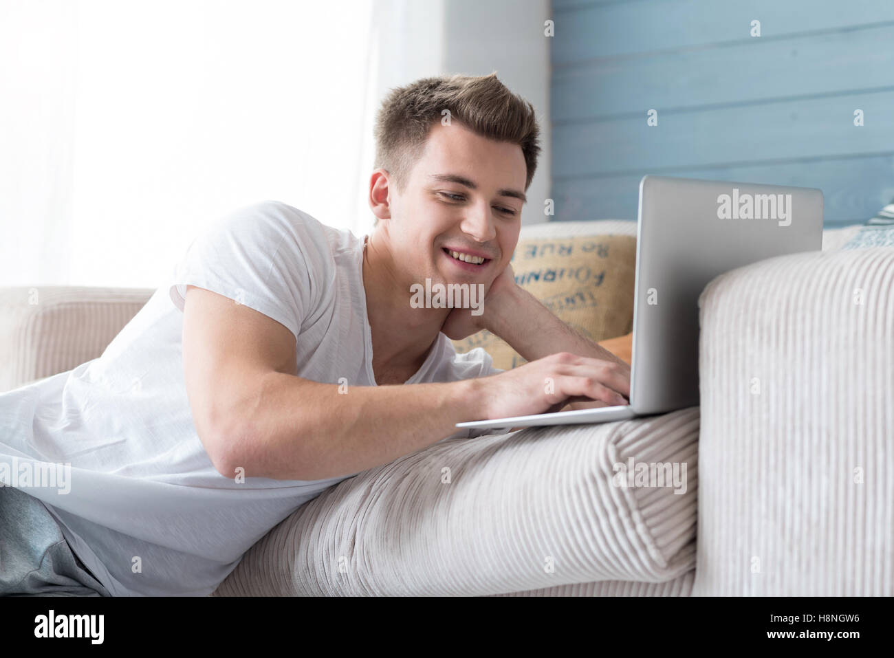 Positive young man using laptop hi-res stock photography and images - Alamy