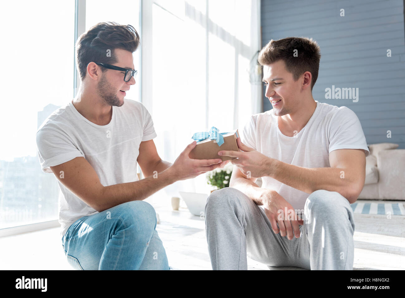 Handsome cheerful man giving a present to his boyfriend Stock Photo - Alamy