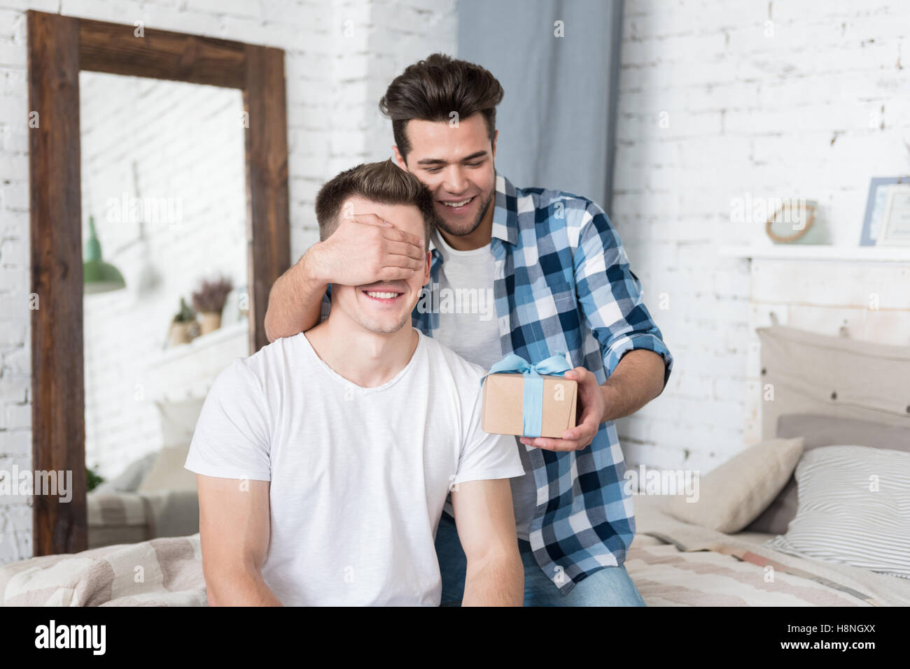 Handsome joyful man giving a present to his male partner Stock Photo ...
