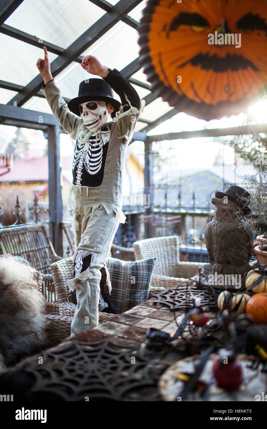 Boy (8-9) wearing skeleton costume raising arms in house Stock Photo ...