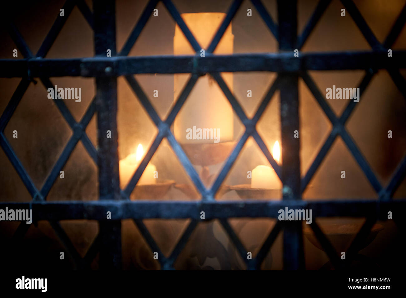 Candles burning behind old fashioned leaded windows Stock Photo - Alamy