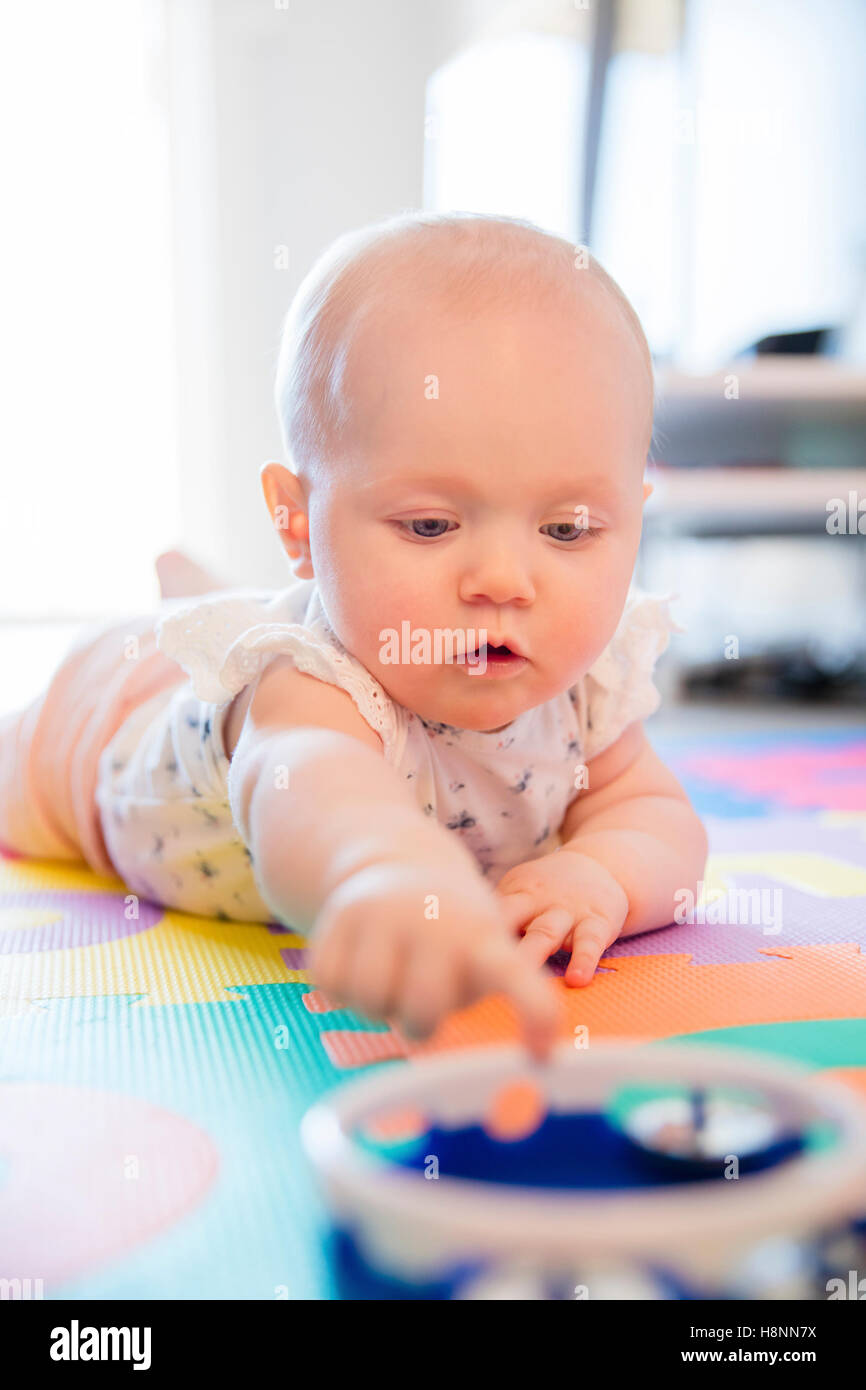 Baby girl with blue eyes playing on mat at floor Stock Photo - Alamy