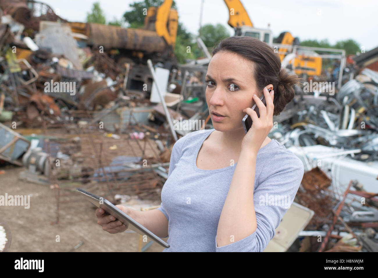 Woman in scrap yard using mobile phone Stock Photo - Alamy