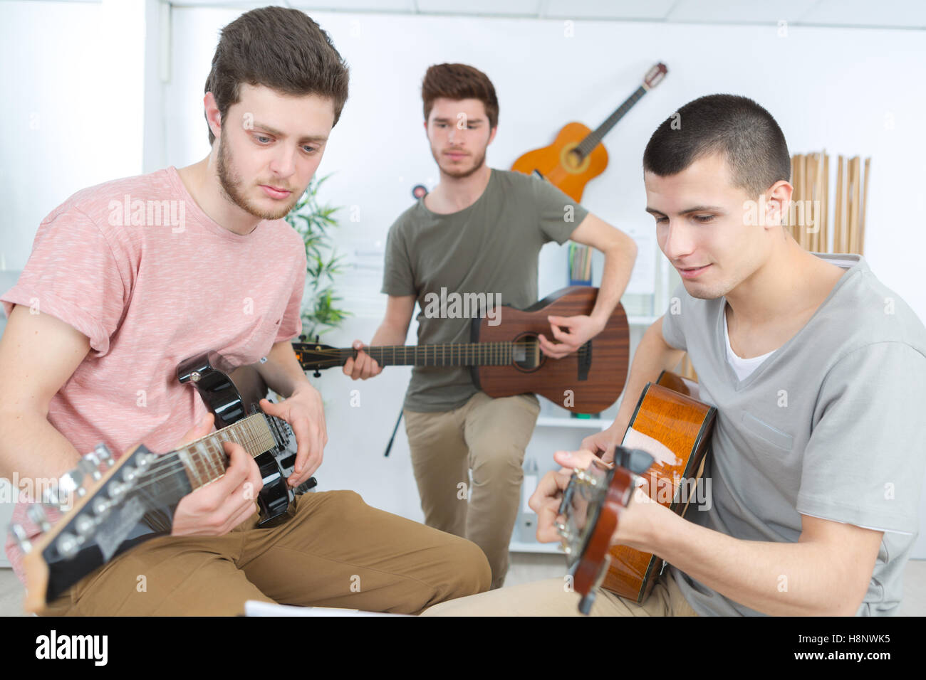 portrait of rock band trio embraced in the studio Stock Photo - Alamy