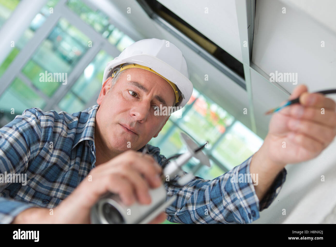 old worker in white helmet repairing Stock Photo - Alamy