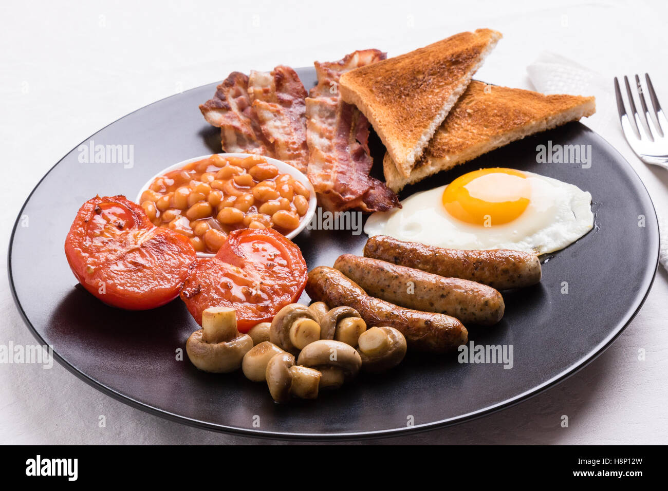 full english breakfast with bacon, sausage, eggs, beans, mushrooms on ...