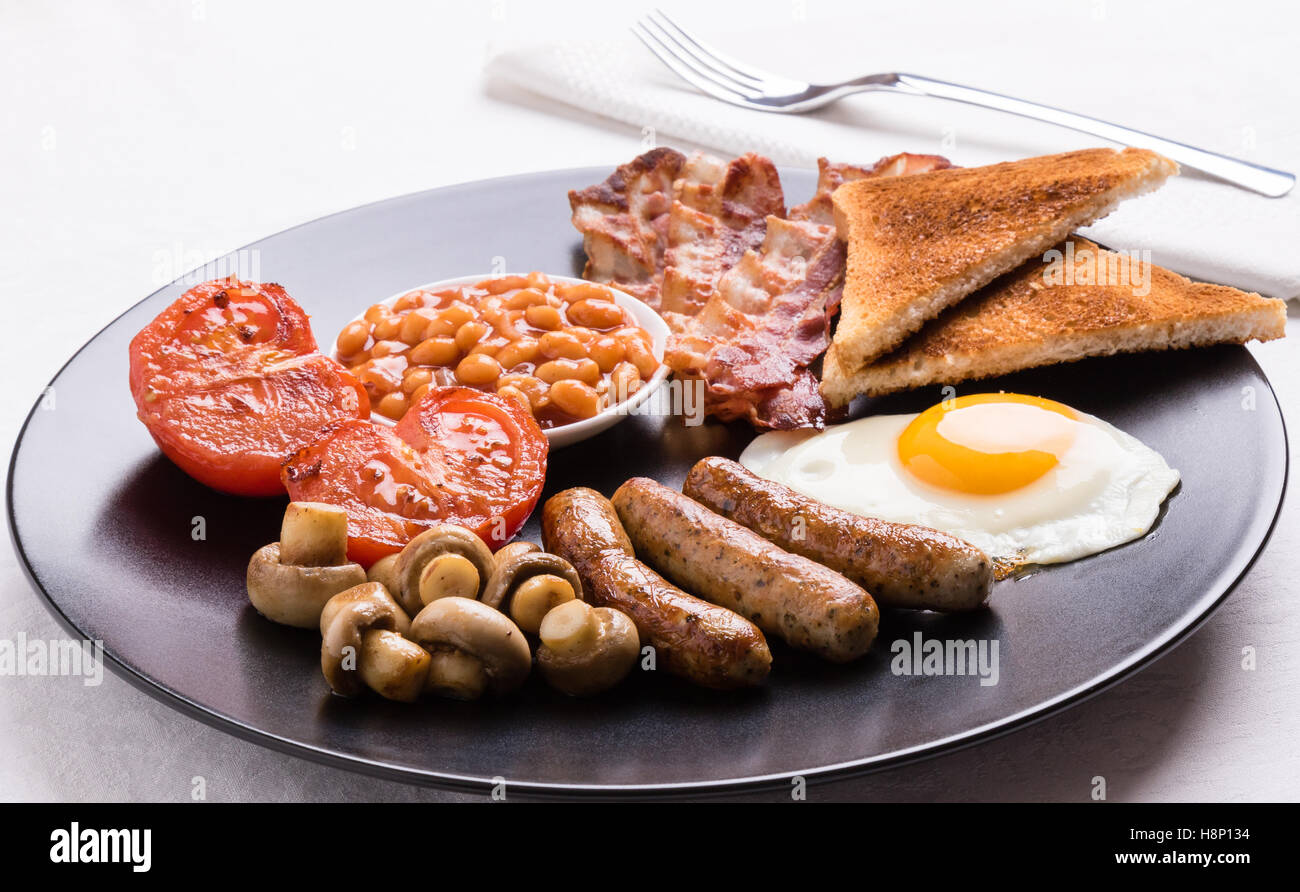 full english breakfast with bacon, sausage, eggs, beans, mushrooms on ...