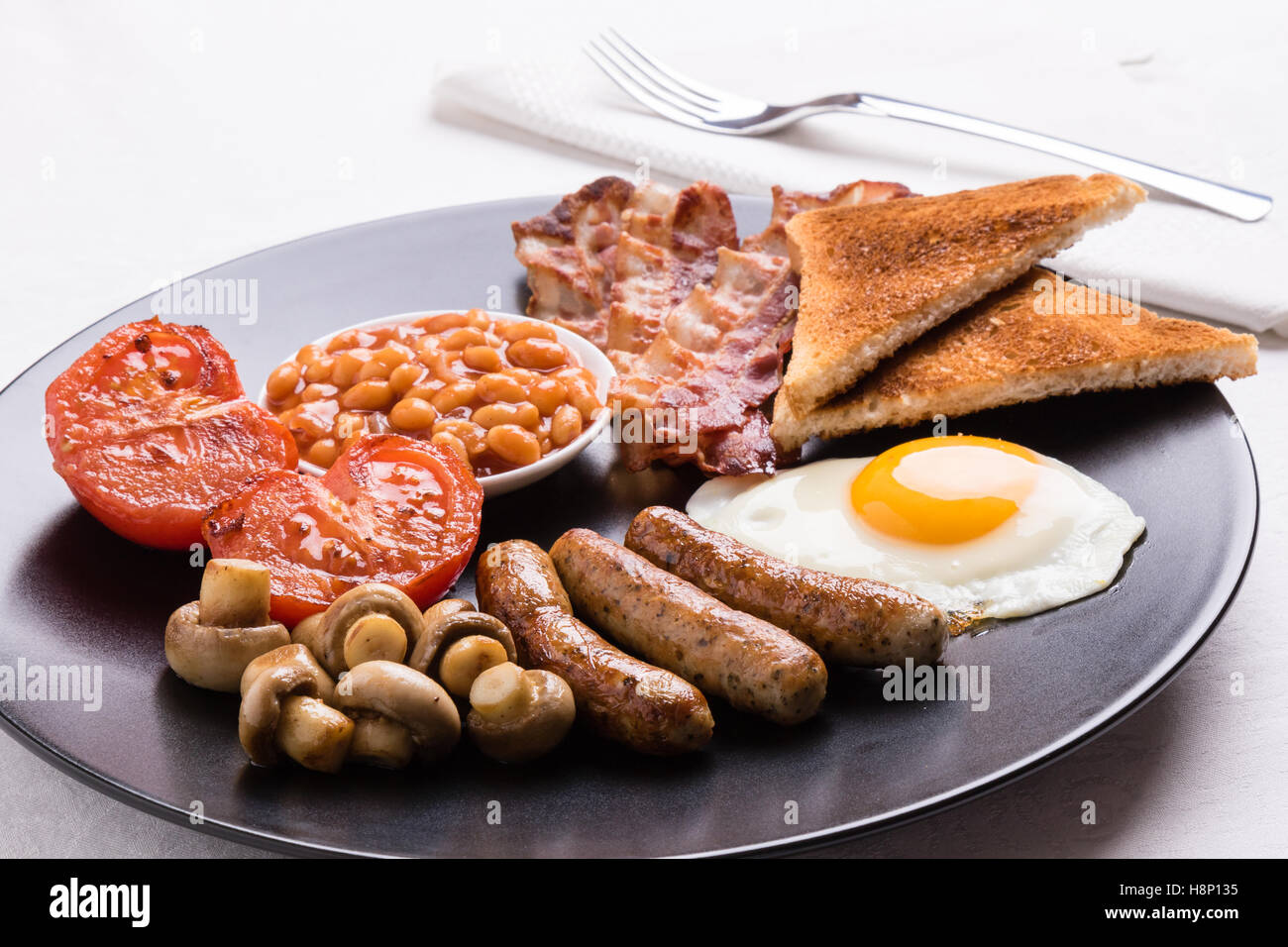full english breakfast with bacon, sausage, eggs, beans, mushrooms on ...